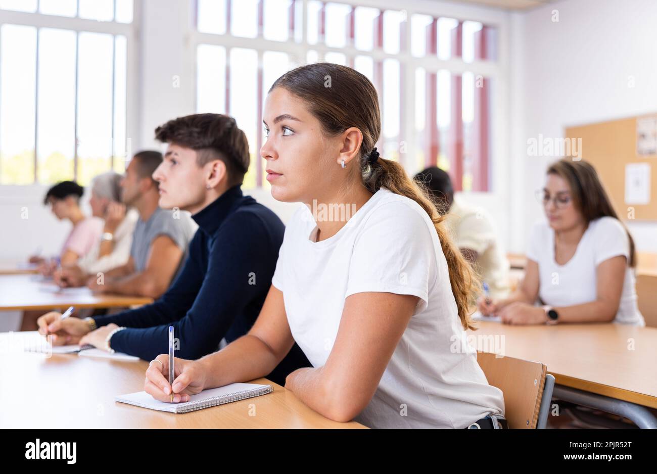 Young girl listening to lecture and taking notes in classroom Stock ...