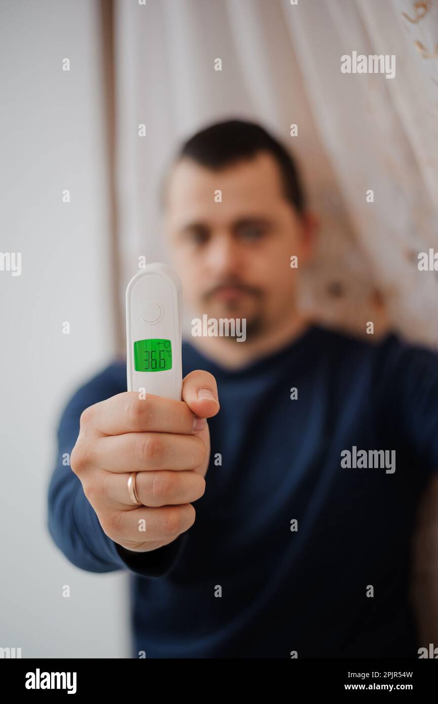 Non-contact thermometer in the hands of a man. Man measures body ...