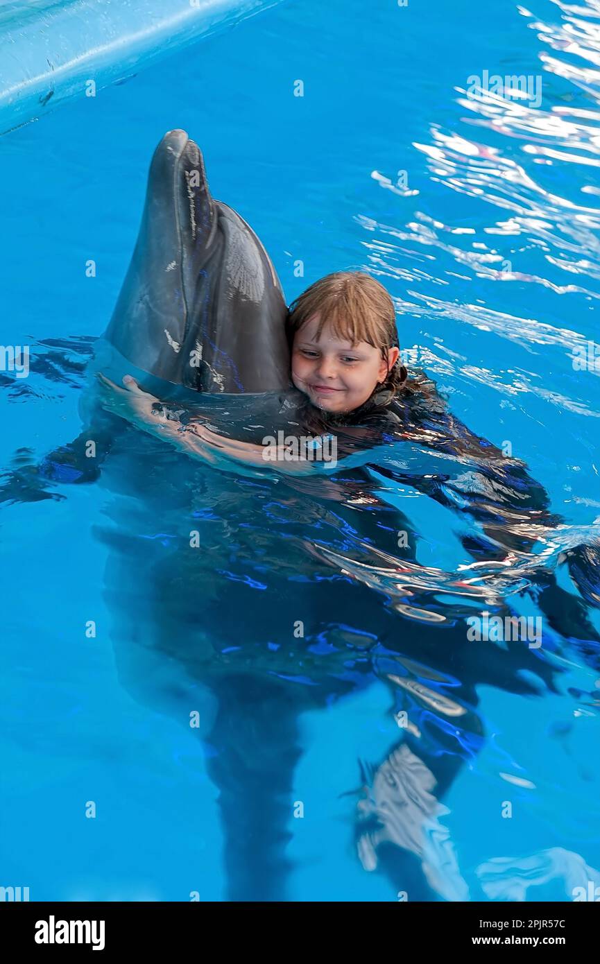 The small girl hugs a dolphin at the dolphin therapy session Stock ...