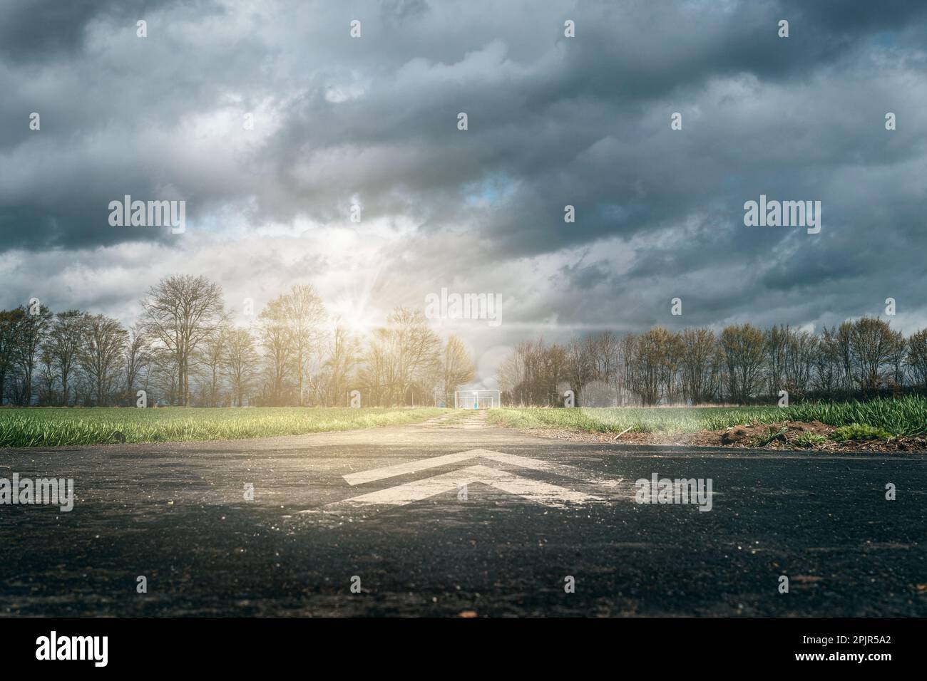 Tarmac path on country road with arrows pointing forward to a gate ...