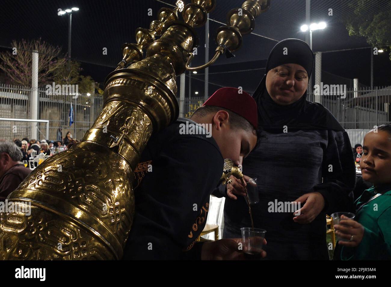 A young Israeli Arab with his copper teapot on his back gives a cold ...