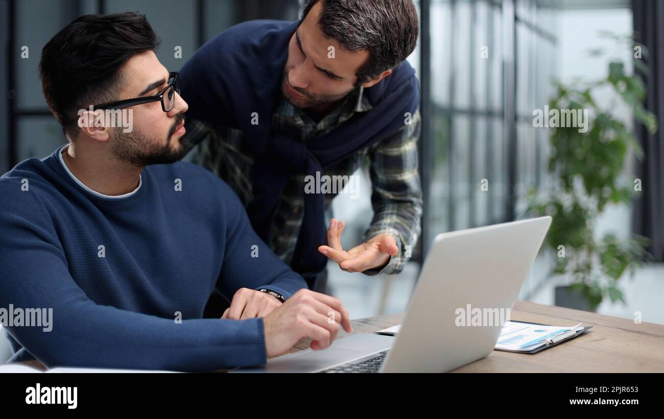 two male colleagues are talking at the table in the office Stock Photo ...