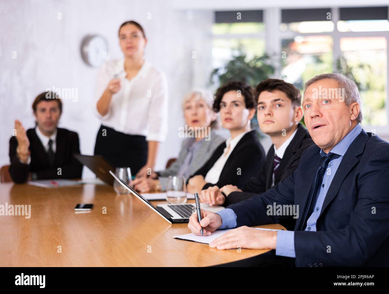 Concentrated young adult old office workers sitting around the table ...