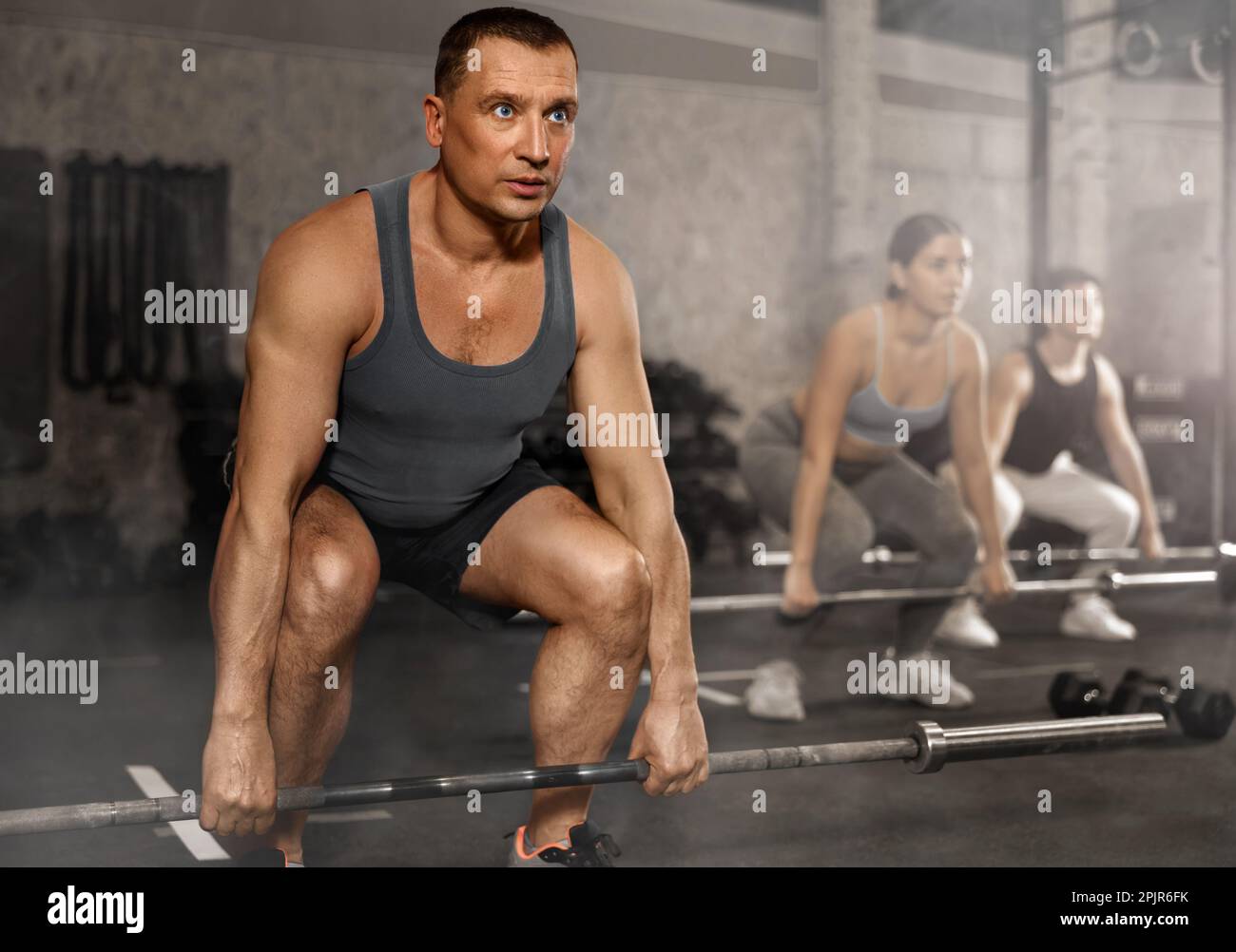 Motivated CrossFit middle-aged male athlete lifting heavy body bar or ...