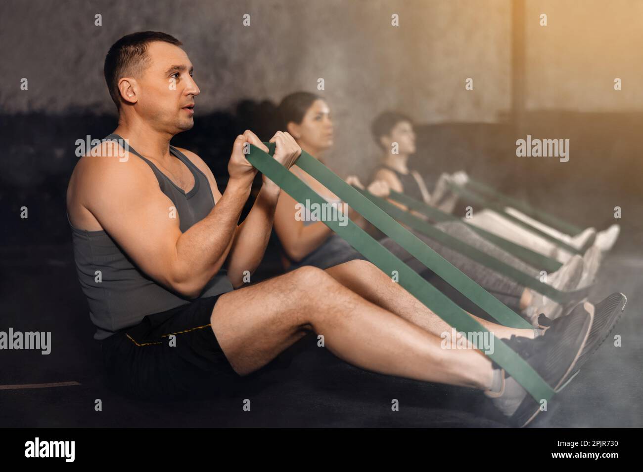Focused man exercising with resistance band loop in gym Stock Photo - Alamy