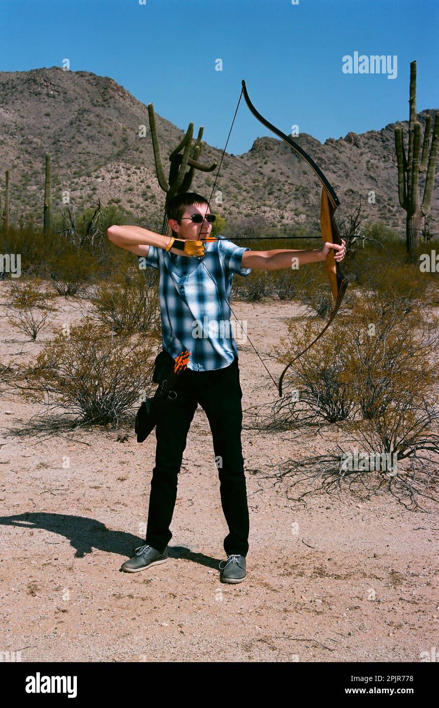 Young man shooting a bow and arrow in the desert Stock Photo - Alamy