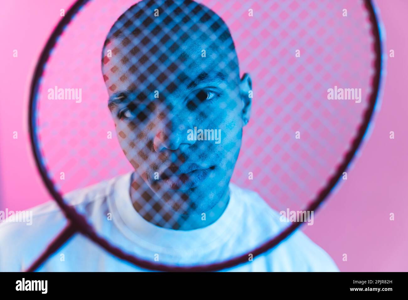 Male model looking at camera and holding badminton racket in front of ...
