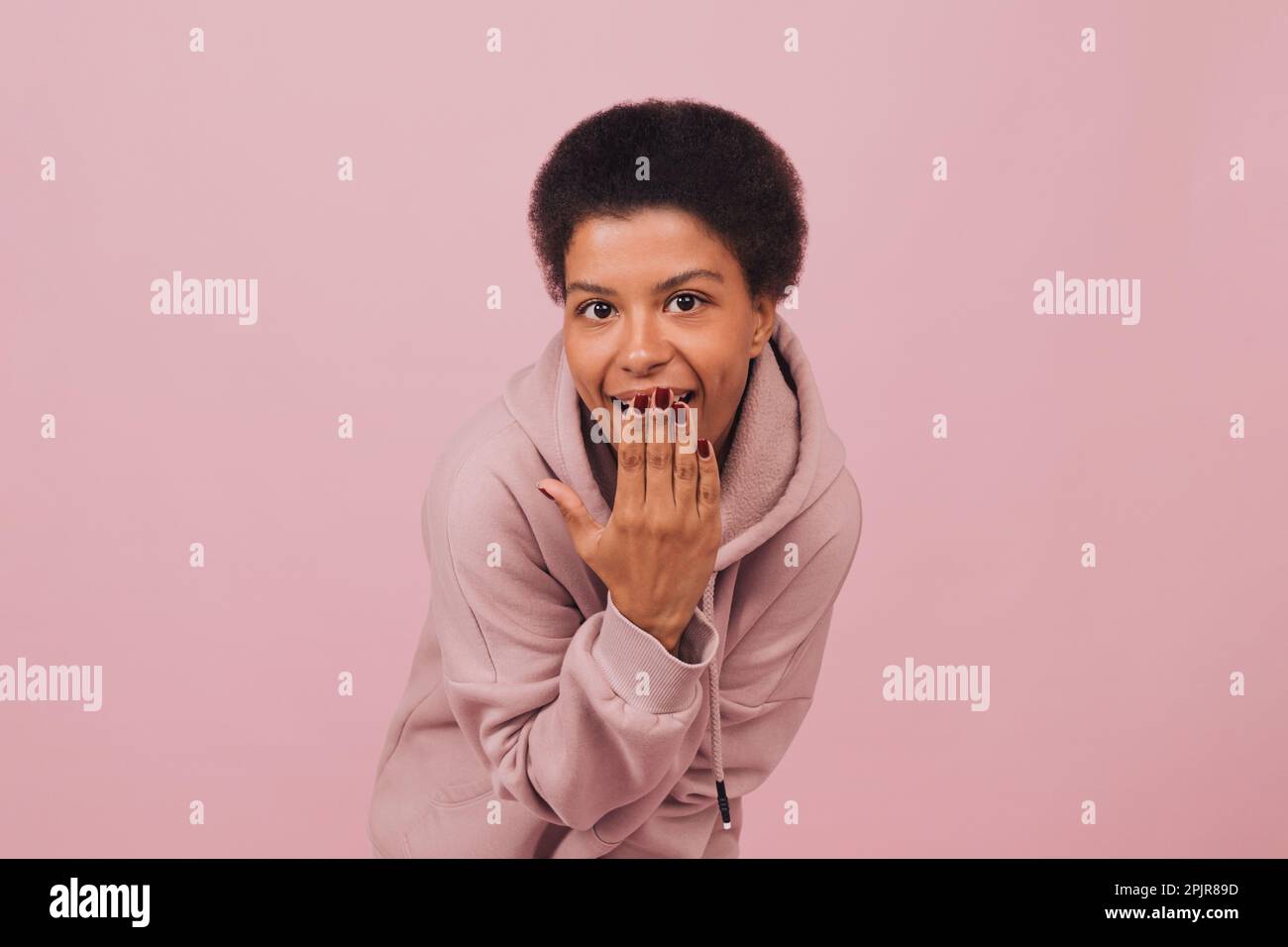 Excited black girl with silence gesture standing on pink backdrop ...