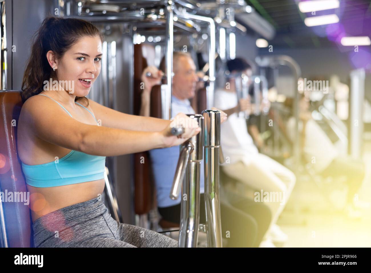 Emotional girl doing chest press in exercise machine in gym Stock Photo ...