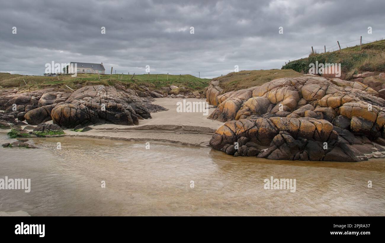 Rocks and beach on ocean coast, farm house on a background, dark gray ...