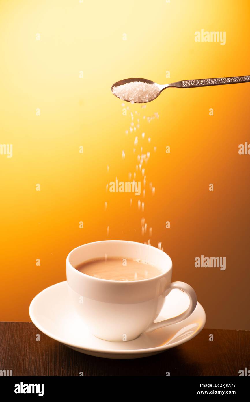 Vertical view of sugar pouring in tea cup Stock Photo - Alamy