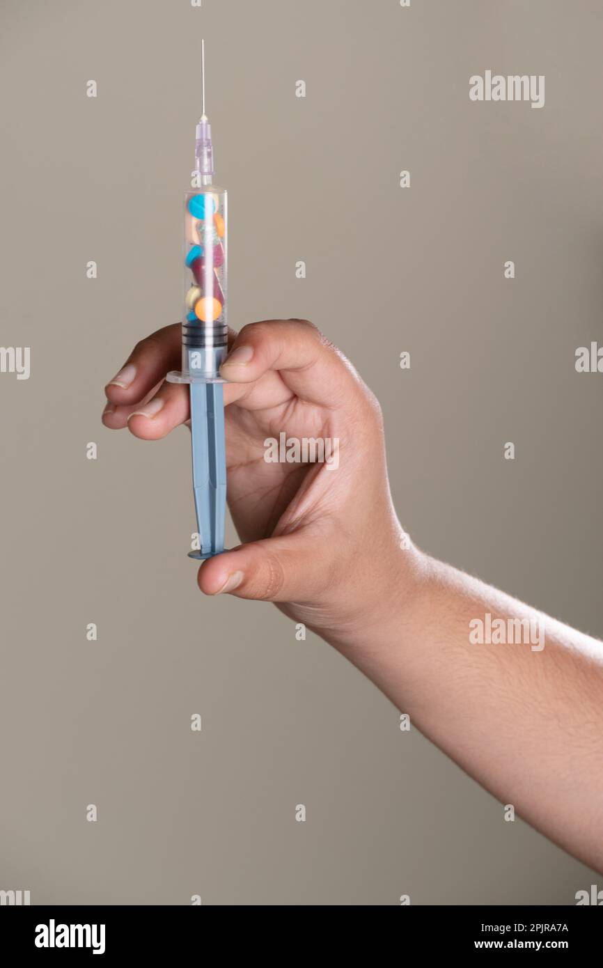 Pills injection in hand on grey background Stock Photo - Alamy