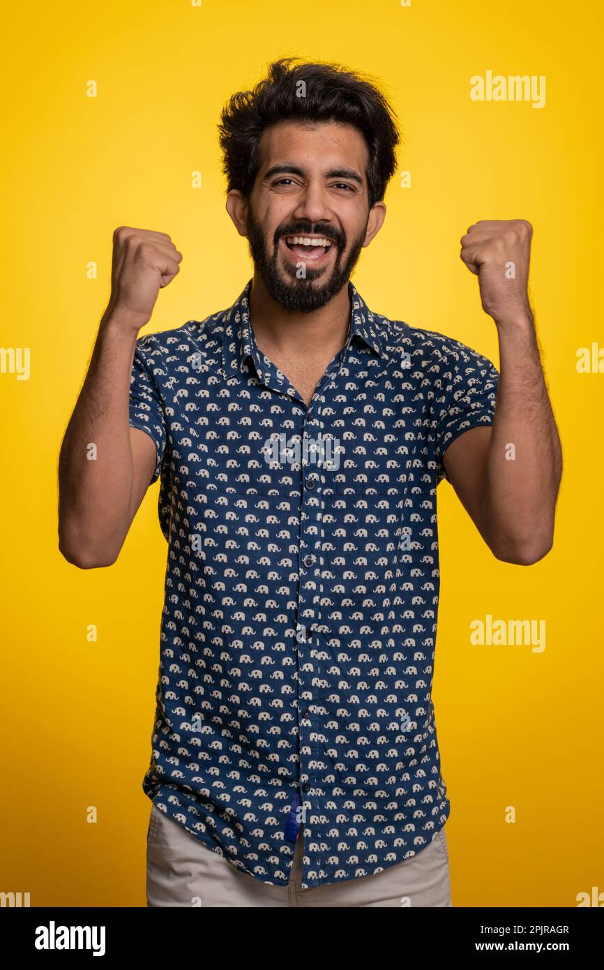Happy joyful indian man shouting, raising fists in gesture I did it ...