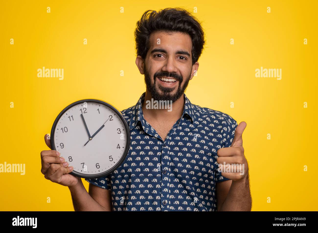 It is your time. Excited happy young indian man showing time on wall ...