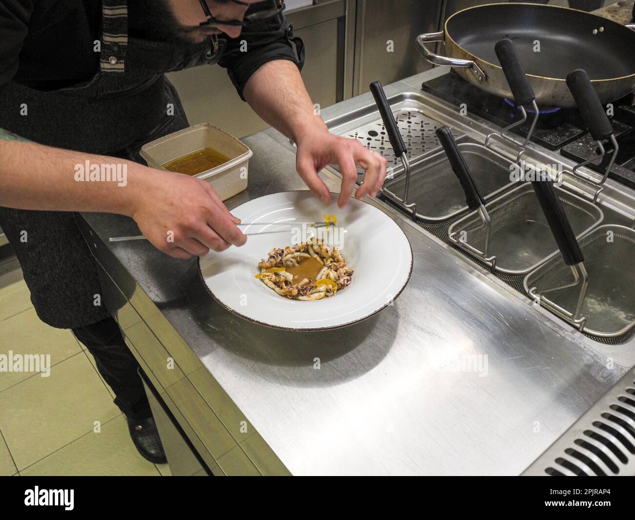 Chef plating pan cooked flambe atlantic squid with potato rich sauce ...