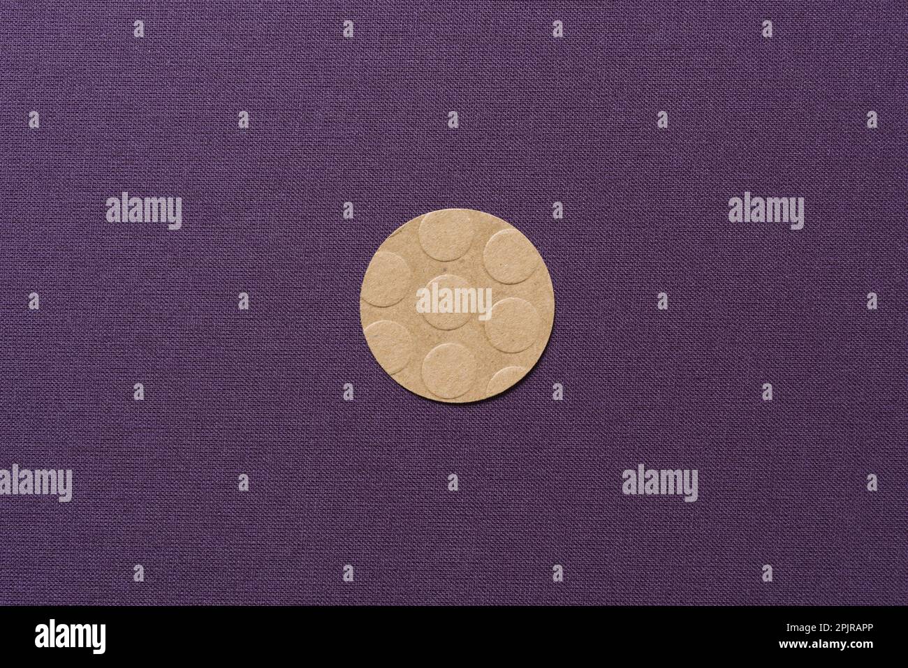paper disc with spots on plum purple fabric background Stock Photo - Alamy