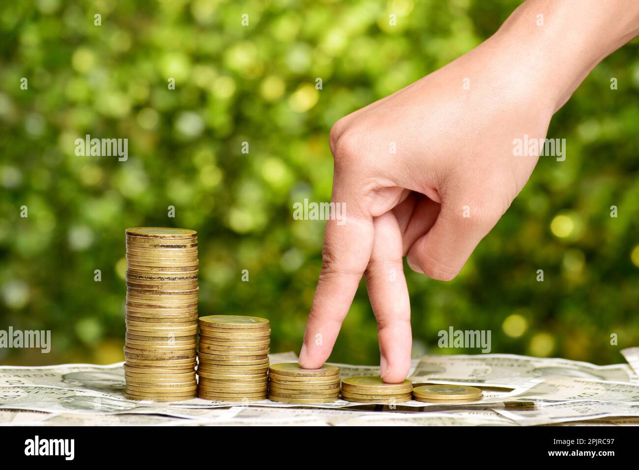 Finger stepping on coin stack Stock Photo - Alamy