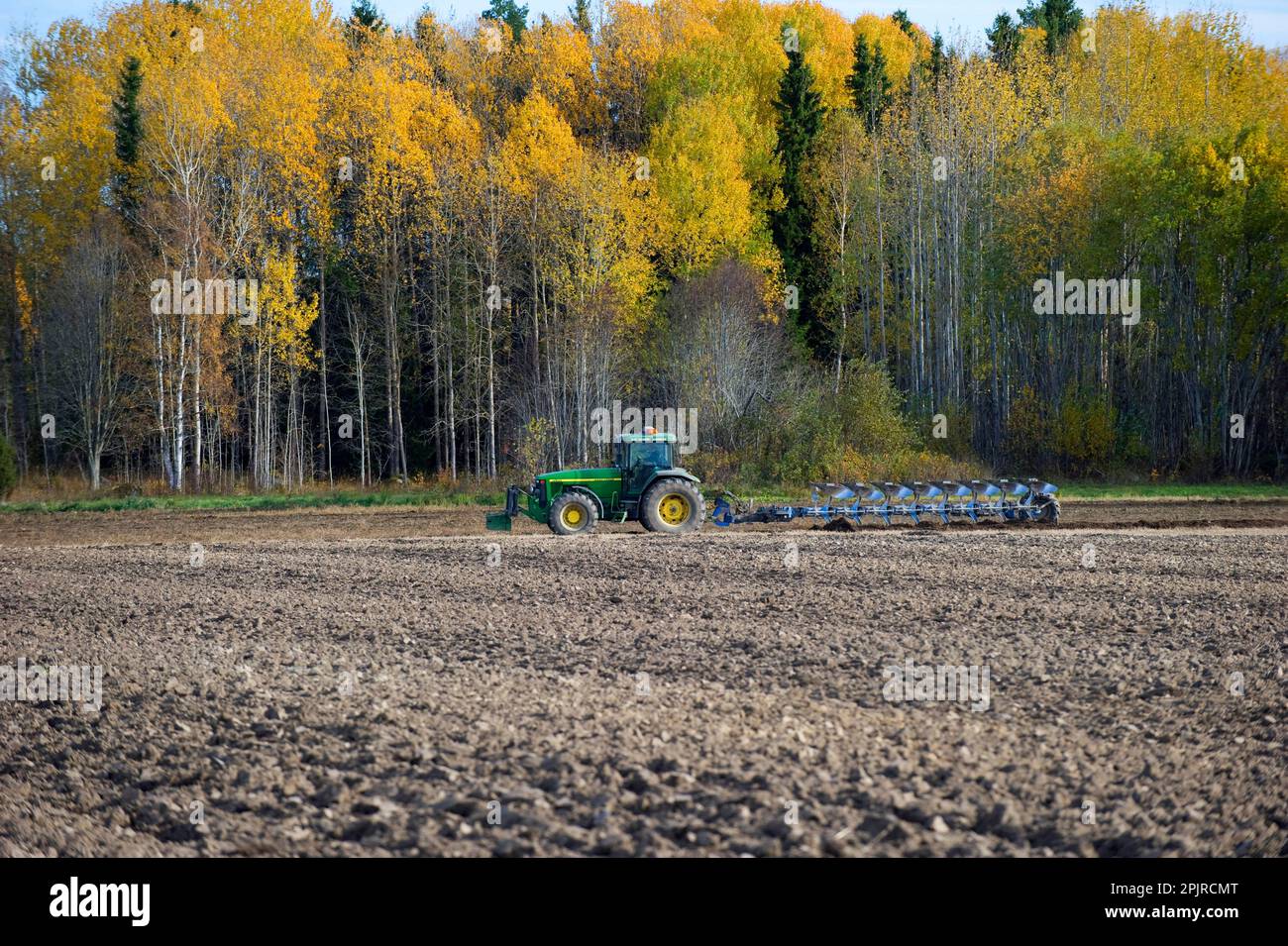 John Deere tractor with eight furrow reversible plough, ploughing ...
