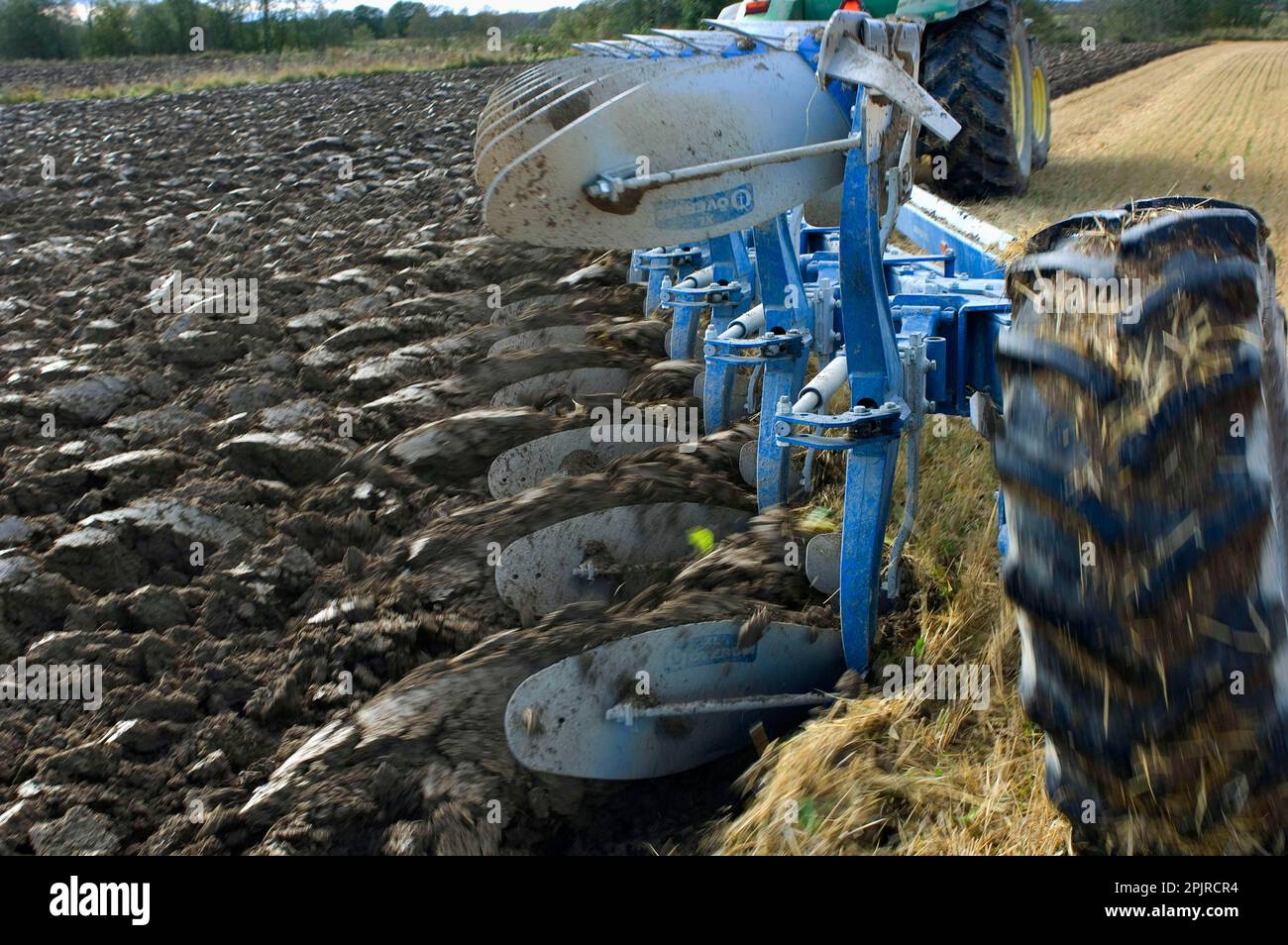 Close-up of a tractor-drawn eight-furrow reversible plough ploughing ...