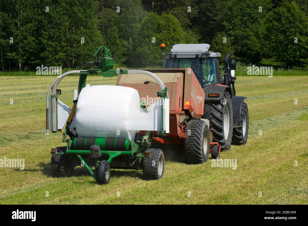 Tractor-drawn baler and mechanical bale wrapper with plastic-wrapped ...