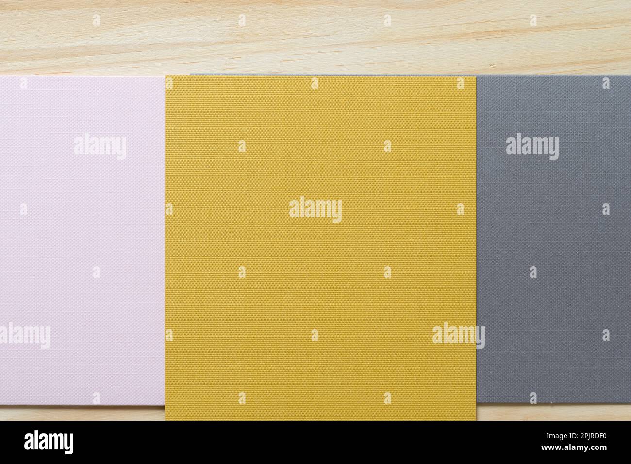 light pink, mustard yellow, and dark grey cards arranged on a wooden ...
