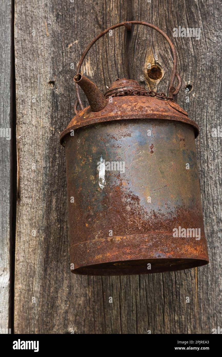 Rusted antique watering can displayed on side wall of wood plank ...