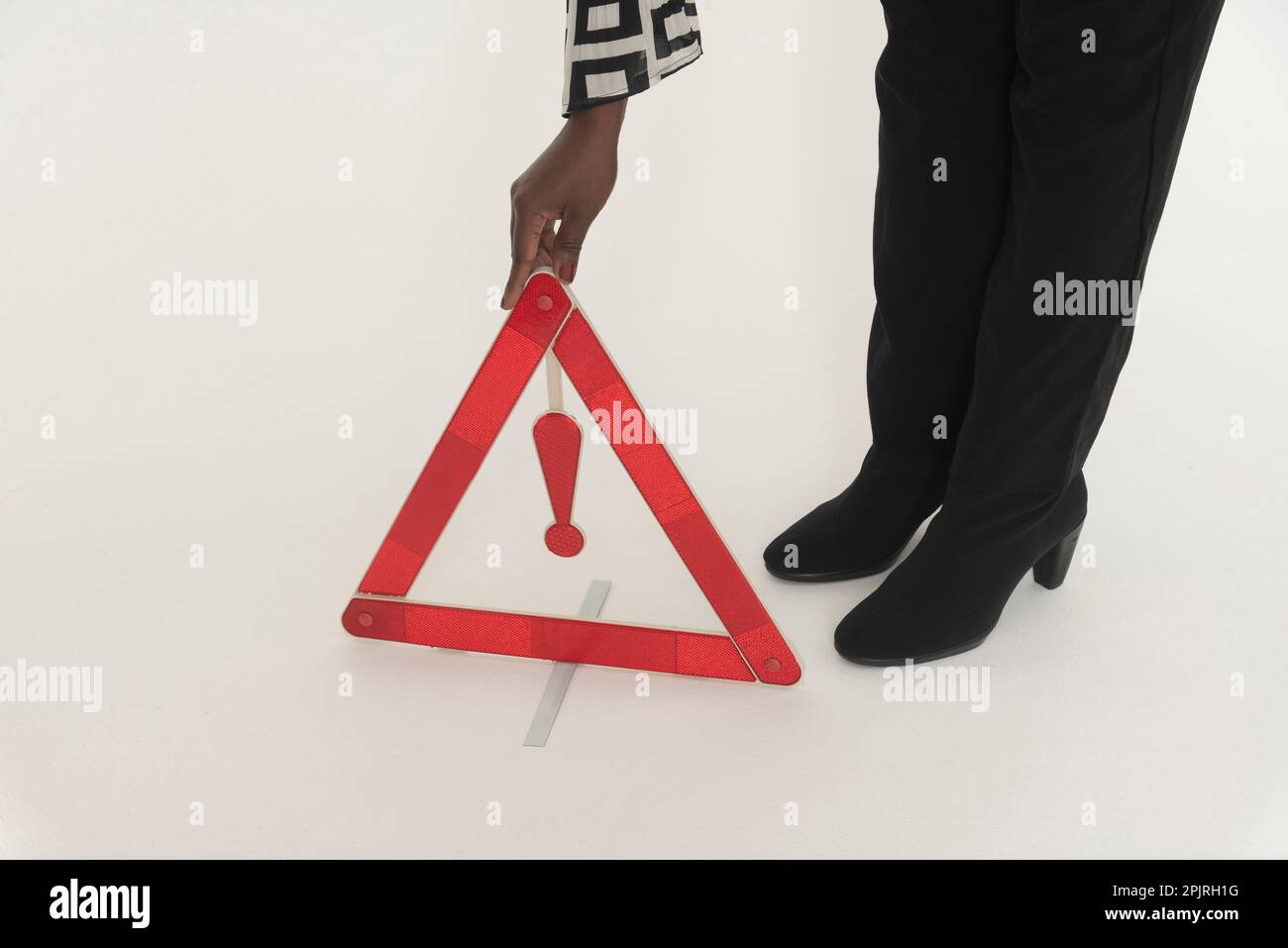 England, UK. 2022. Woman driver placing a red danger triangle to warn ...