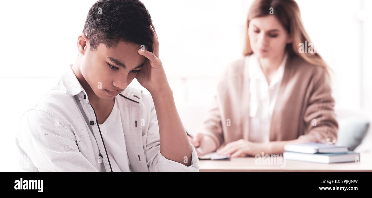 Young female psychologist working with teenage boy in office. Banner ...