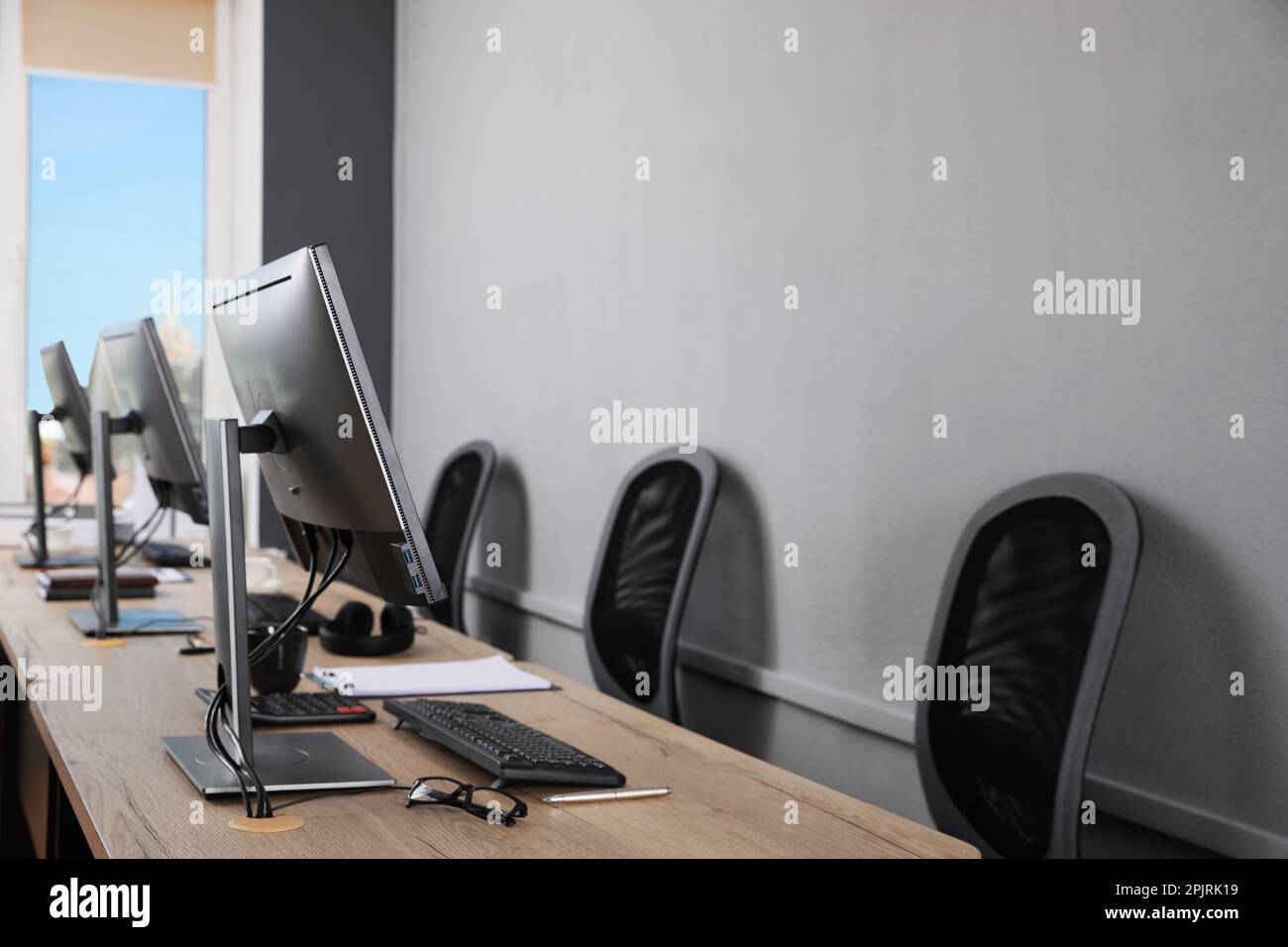 Open office interior. Modern workplaces with computers near light grey ...