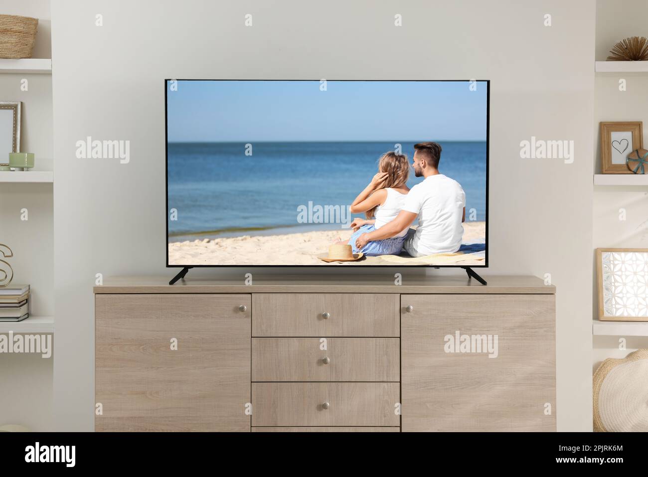 Modern TV set on wooden stand in room. Scene of romantic movie on ...