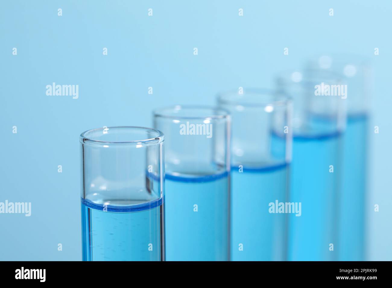 Test tubes with reagents on light blue background, closeup. Laboratory ...