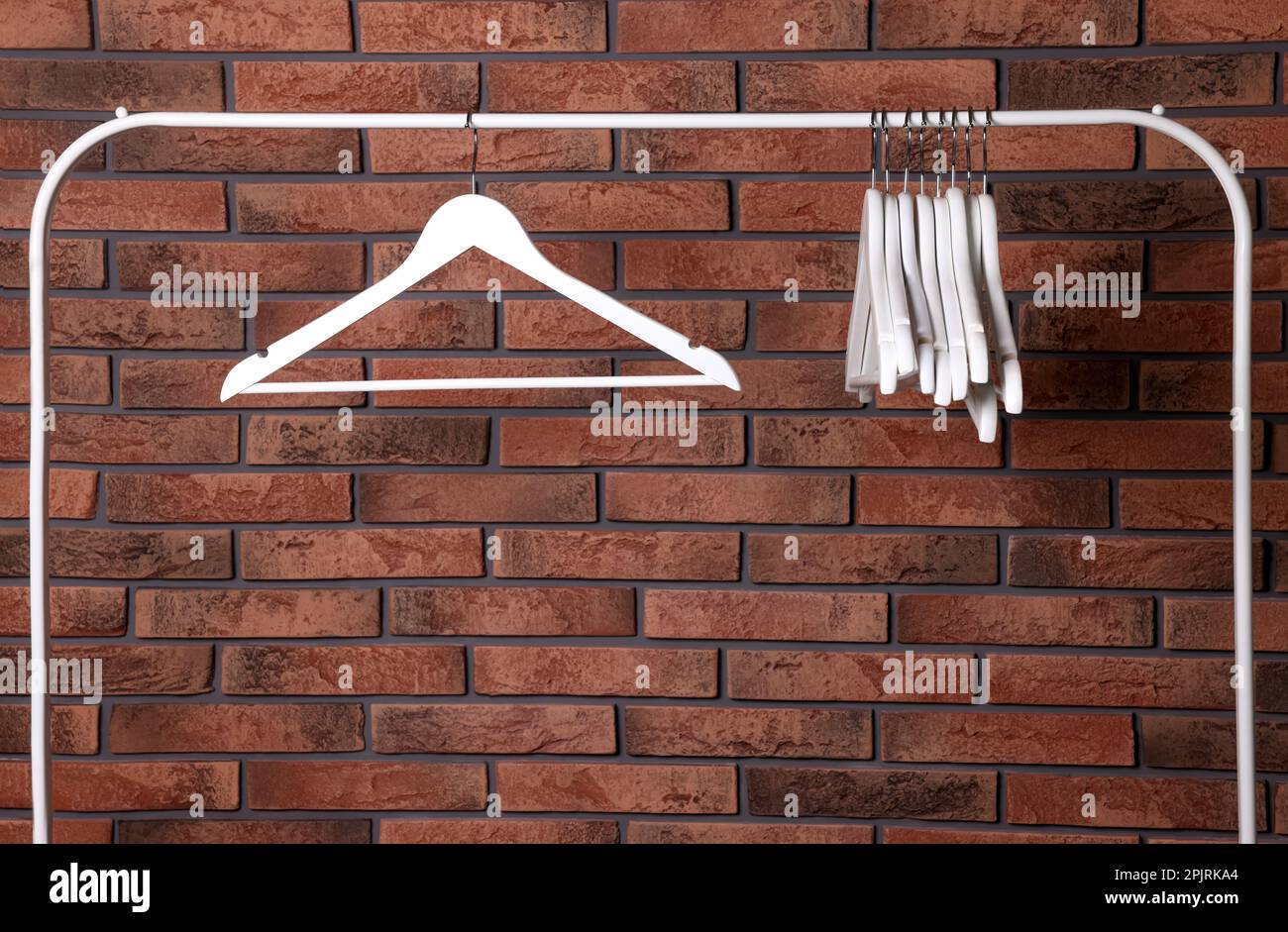 White clothes hangers on rack near red brick wall. Space for text Stock ...