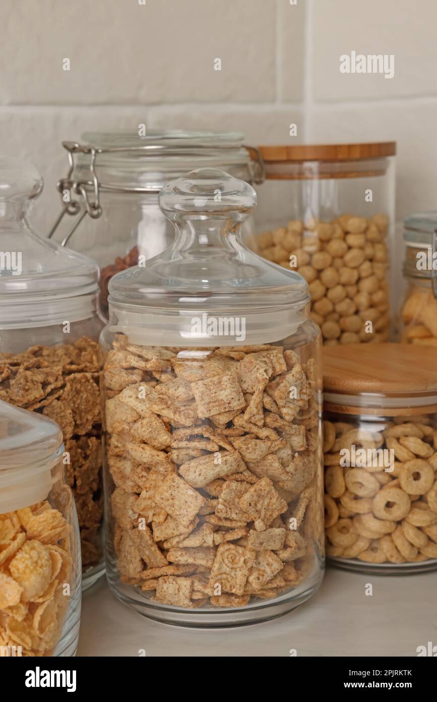 Glass containers with different breakfast cereals on white countertop ...
