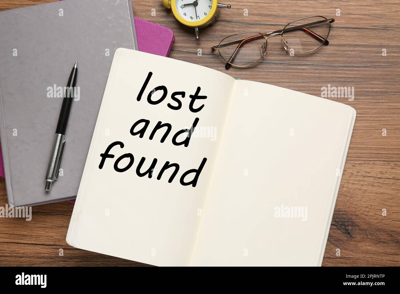 Notebook with phrase Lost and Found, pen, glasses and alarm clock on ...