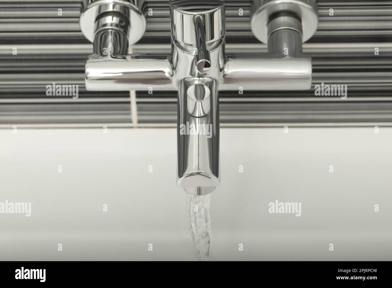 Water flowing from bath tap installed on black and white wall, above ...