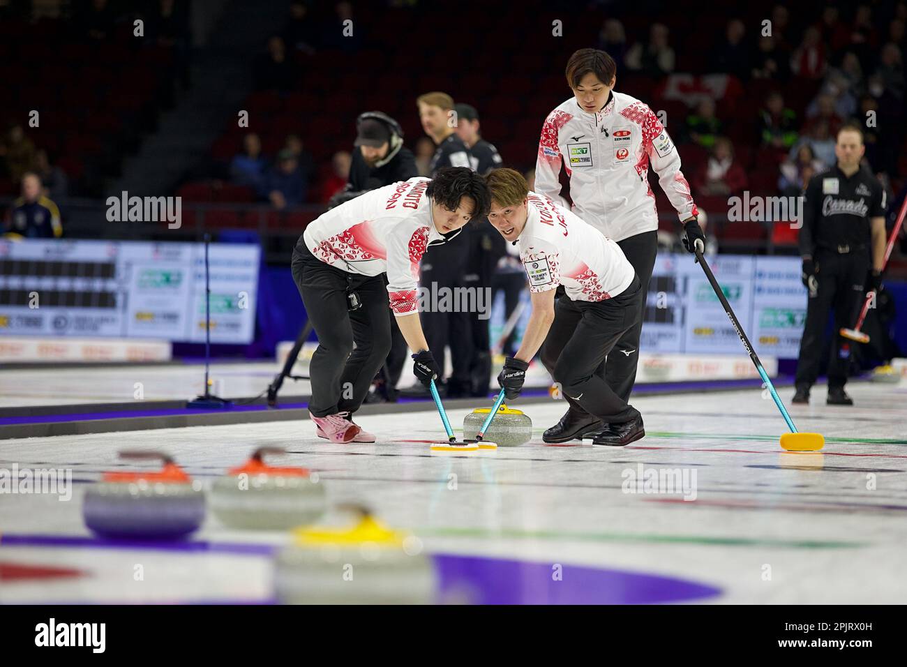 Riku Yanagisawa (rear) follows his shot as Takeru Yamamoto (L) and Satoshi Koizumi (R) sweep ...