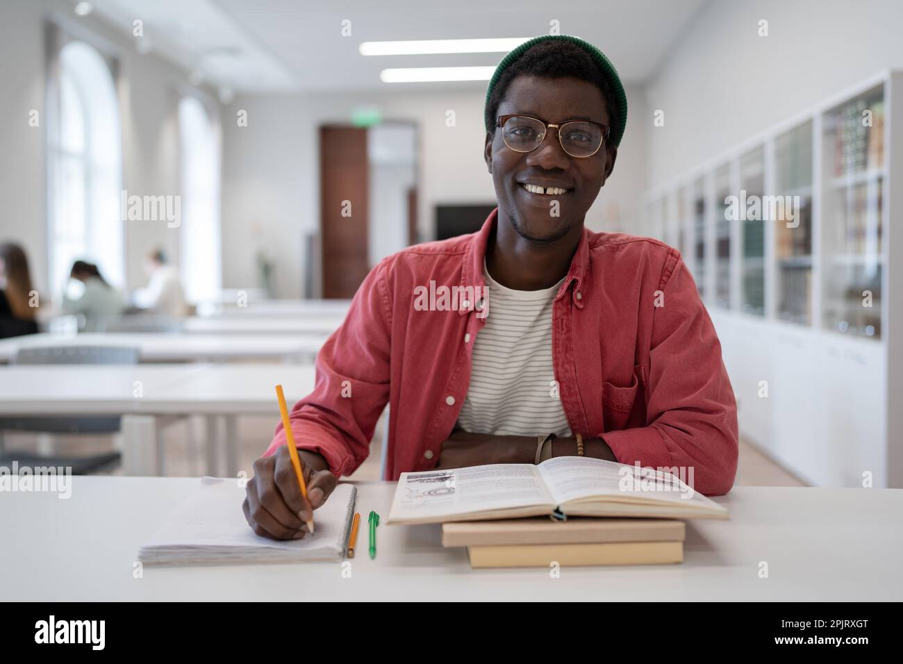 African american young man studying in university library making notes ...