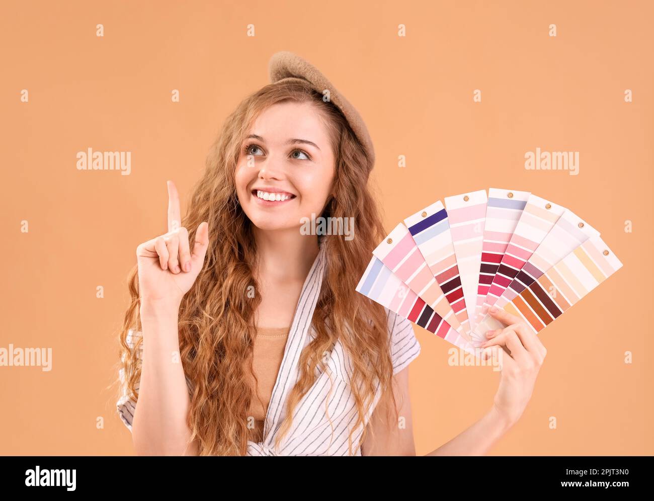 Female artist with paint color palettes pointing at something on beige ...