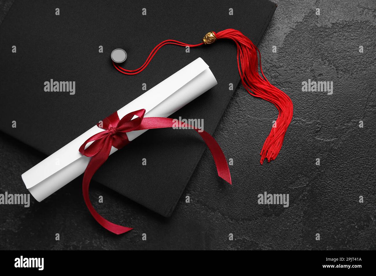 Diploma with red ribbon and graduation hat on black table Stock Photo ...