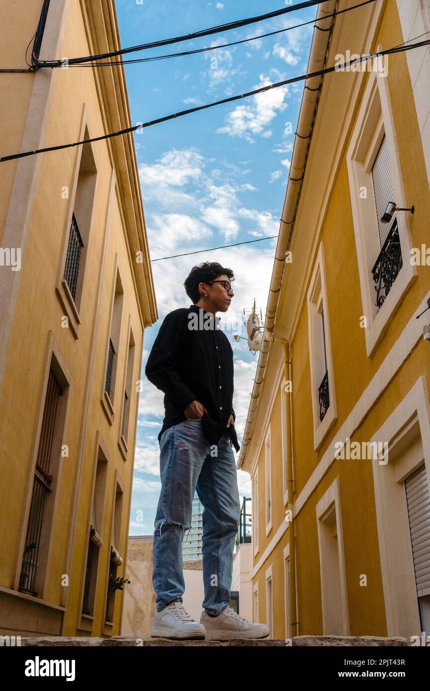 Young transgender man posing outdoors in the narrow street of a town ...