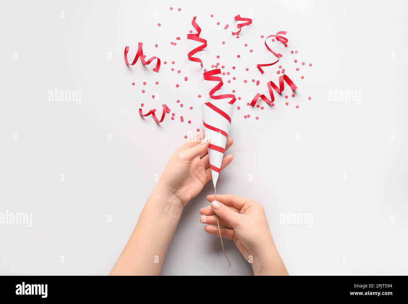 Female hands with party popper and confetti on light background Stock ...