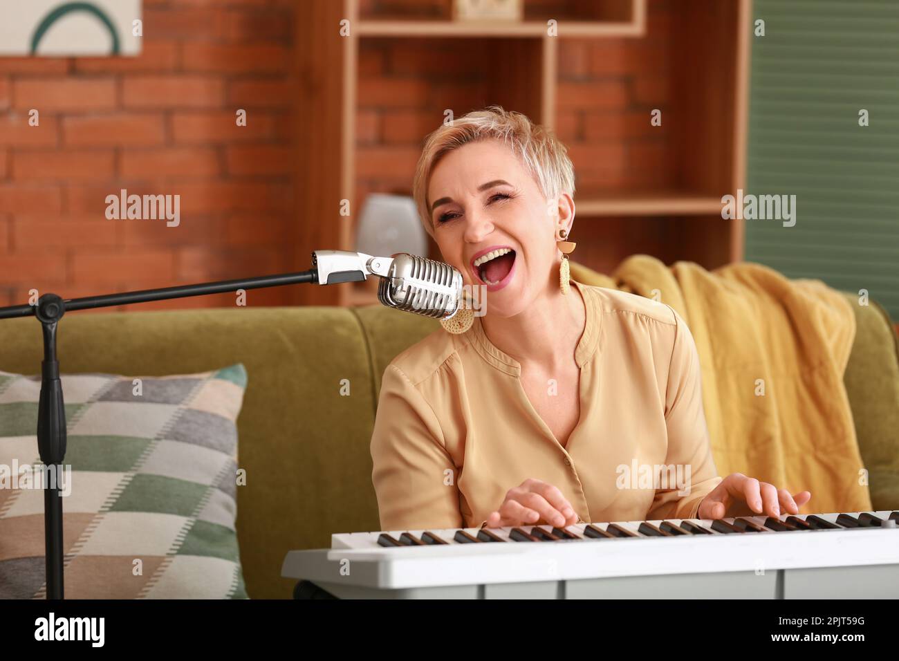 Mature female musician playing synthesizer and singing at home Stock ...