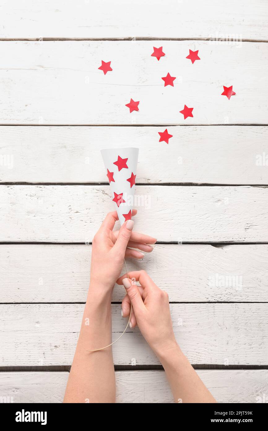 Female hands with party popper and confetti on wooden background Stock ...