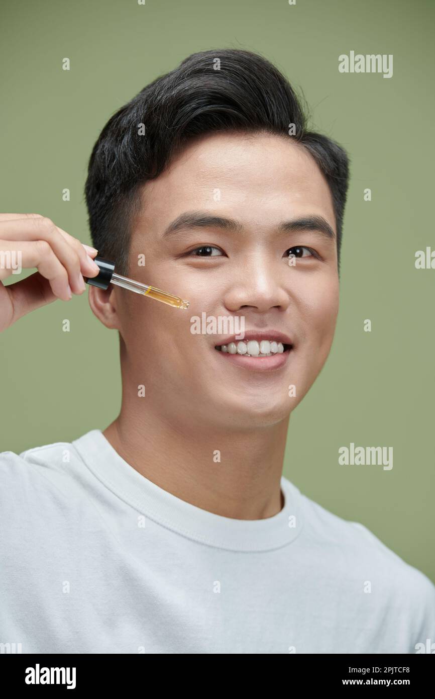 Selective focus of handsome asian man using pipette for applying serum ...