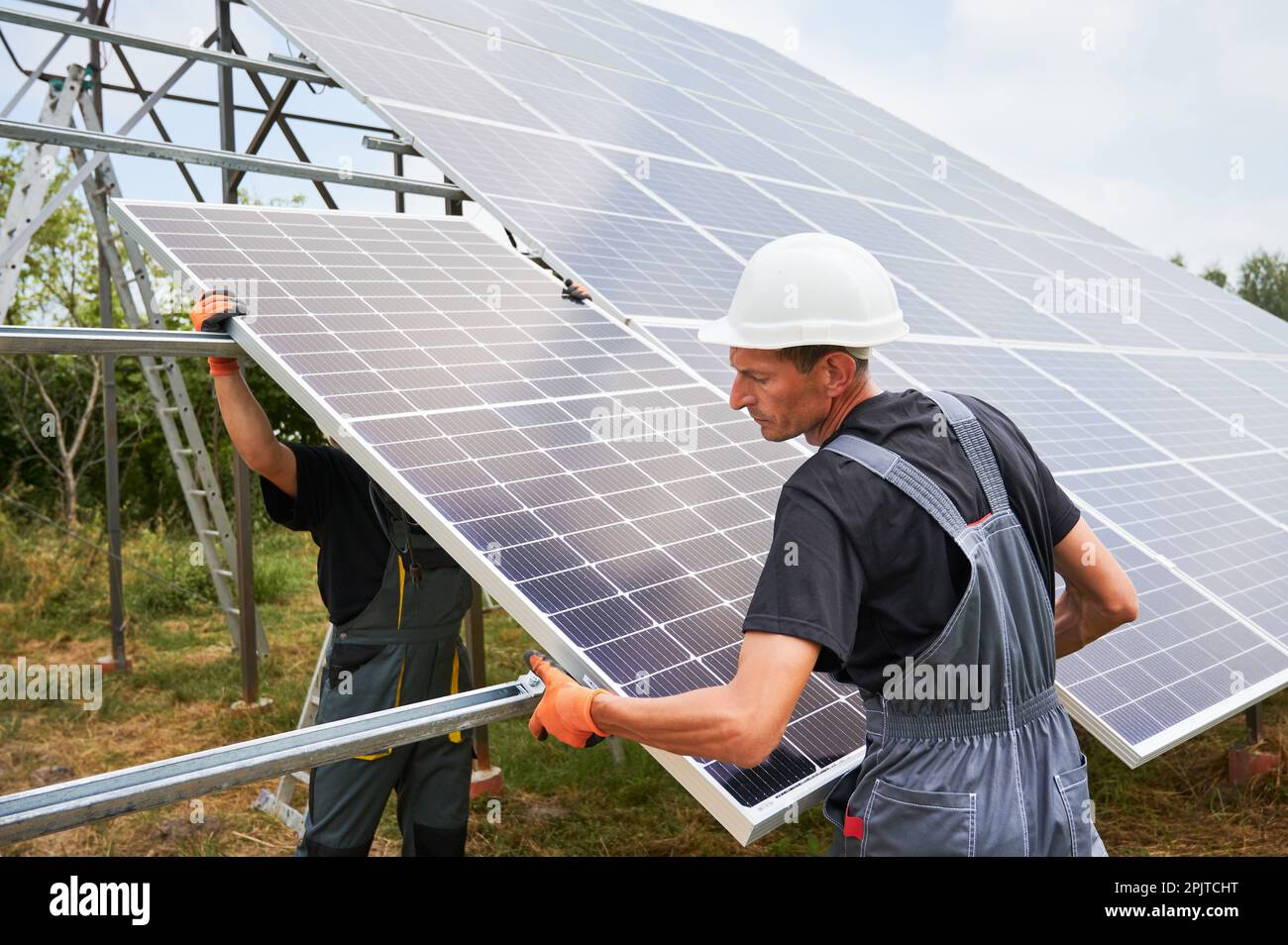 Man engineer solar installer placing solar module on metal rails with ...