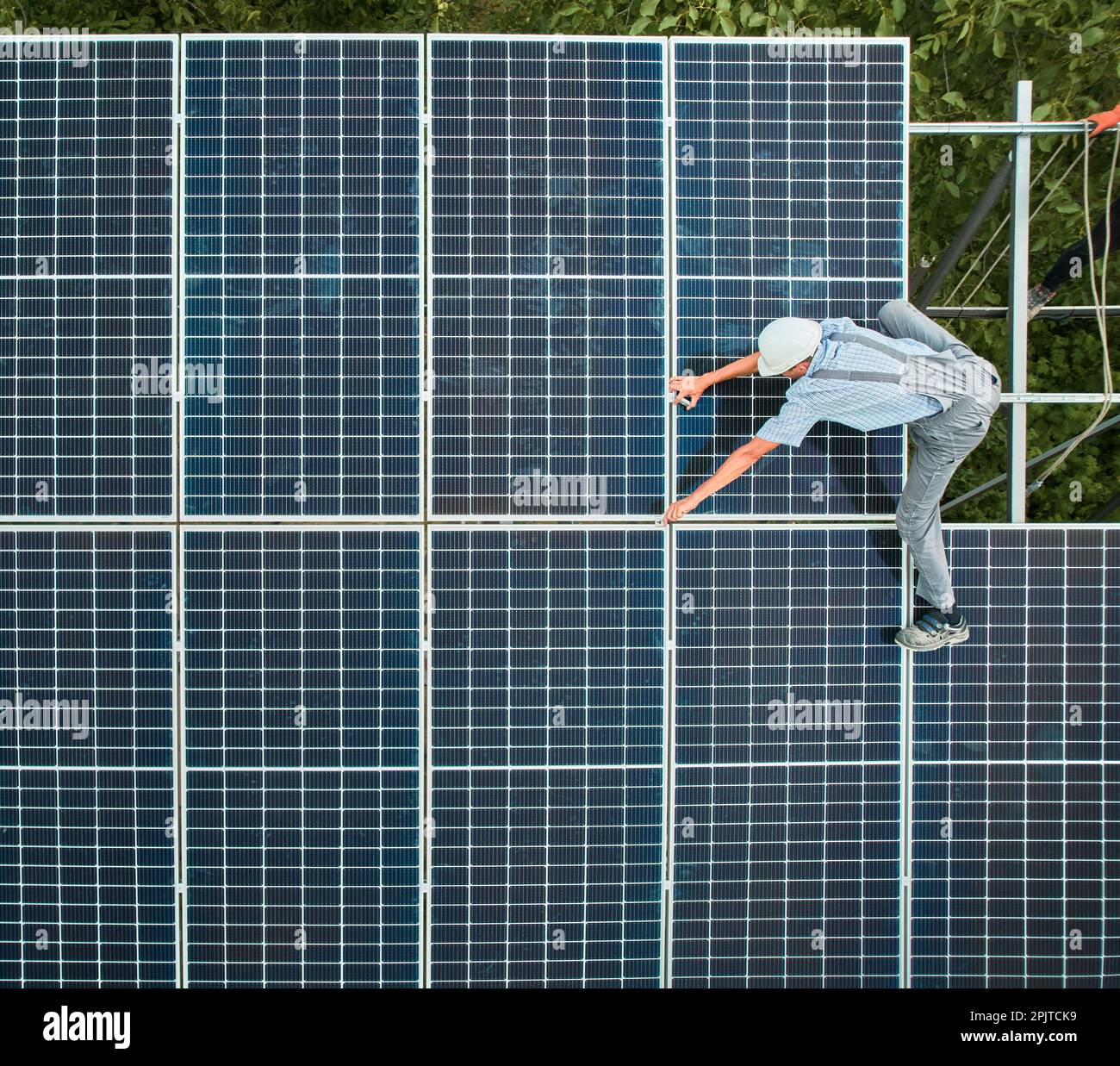 Aerial view of man technician installing solar panels to high steel ...