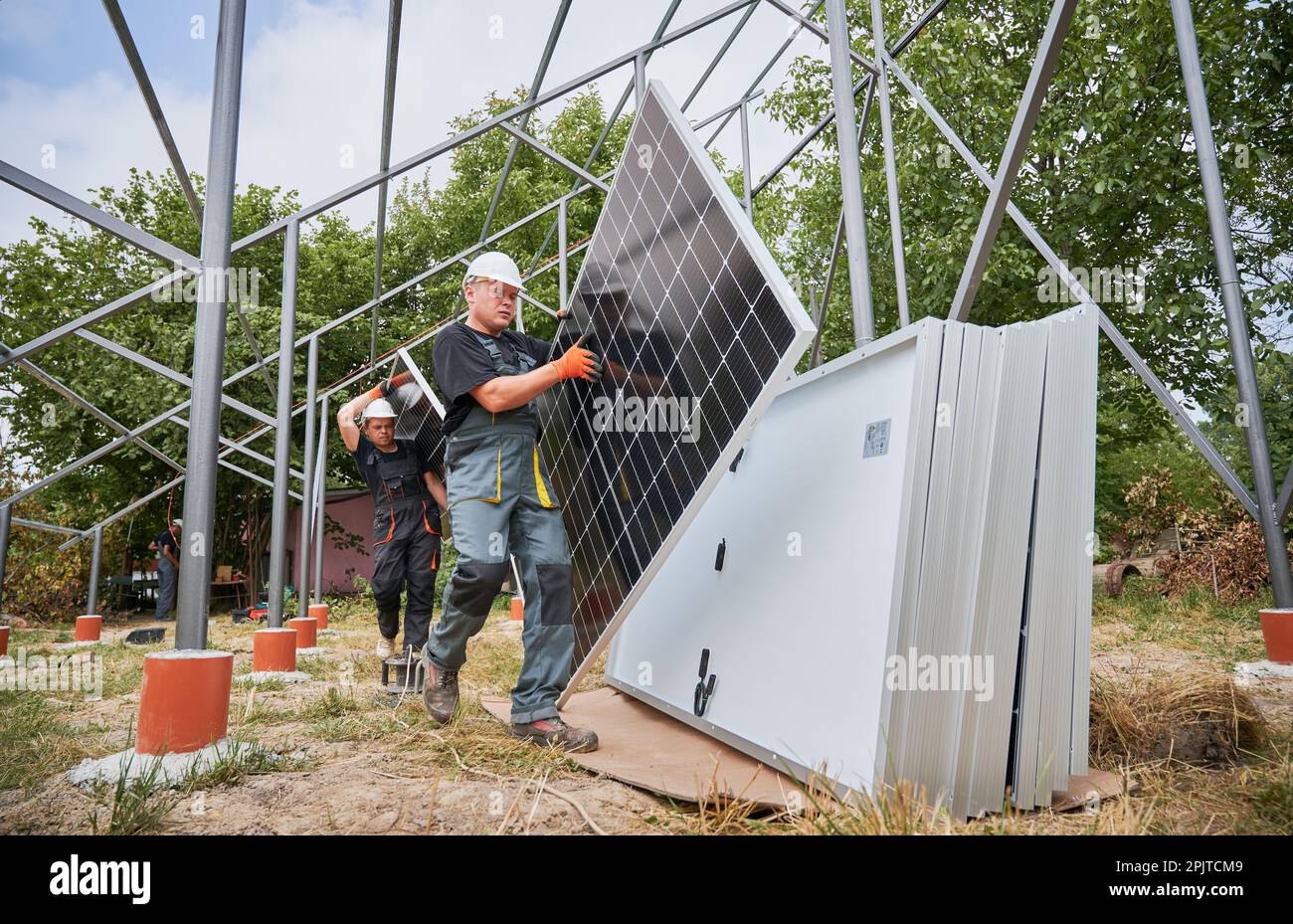 Workers carrying solar panels for installing in field. European men ...