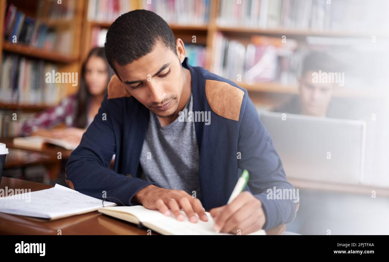 Working diligently. a handsome young student working diligently in his ...
