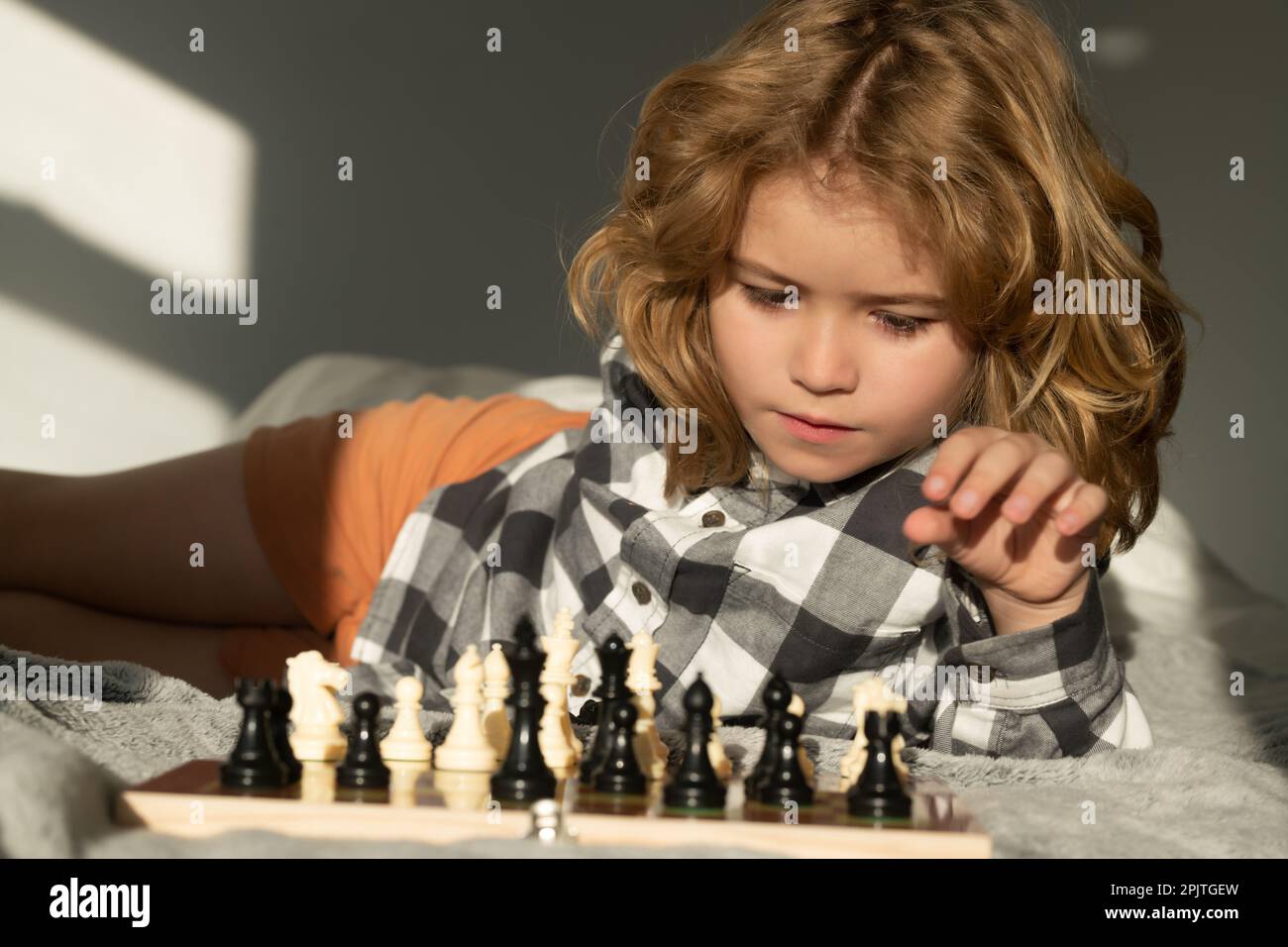 Cute child playing chess at home. Kid thinking about chess. The concept ...
