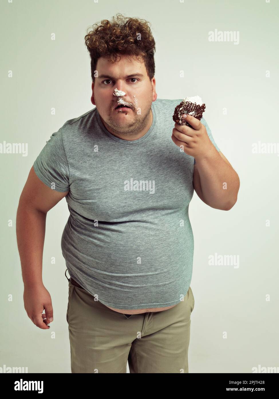 Is there something on my face. an overweight man messily eating a slice ...